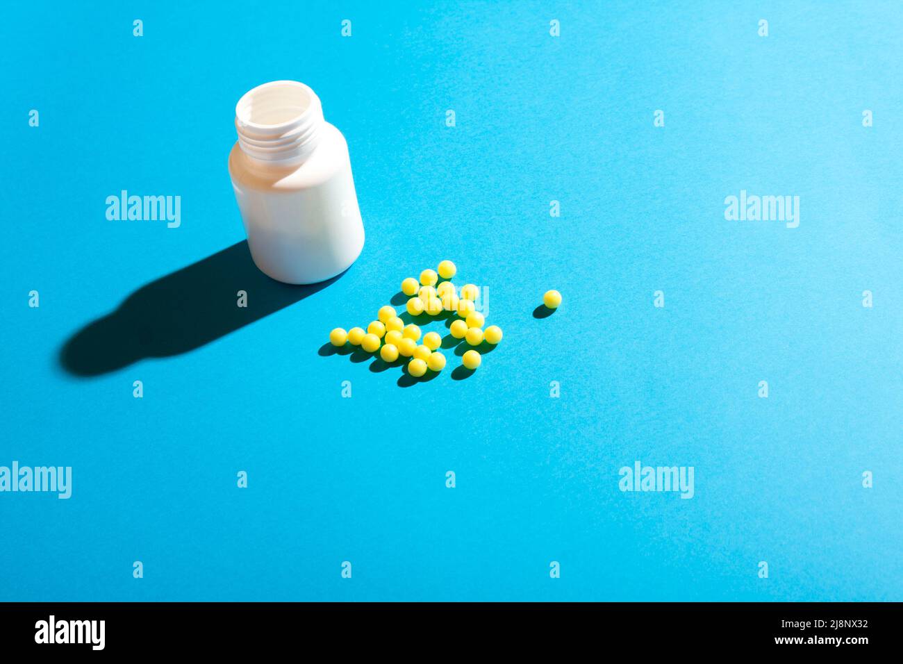Round yellow ball pills and a plastic bottle on blue background Stock ...