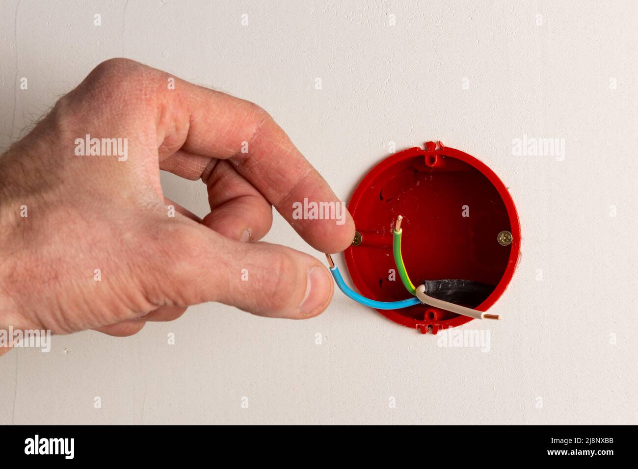 The hand touches uninsulated electrical wires that stick out of the ...