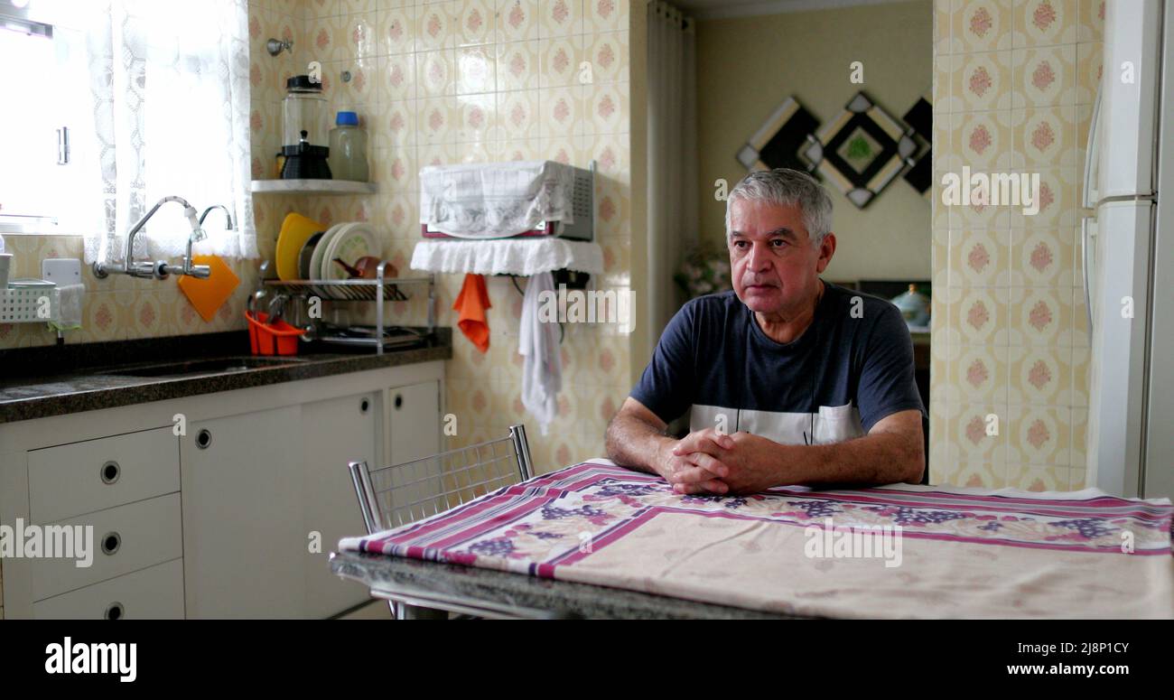 Older man sitting at kitchen table alone Stock Photo - Alamy