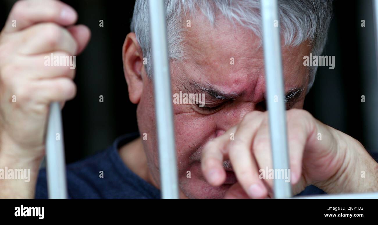 Older man imprisoned behind bars crying. Senior person suffering Stock ...