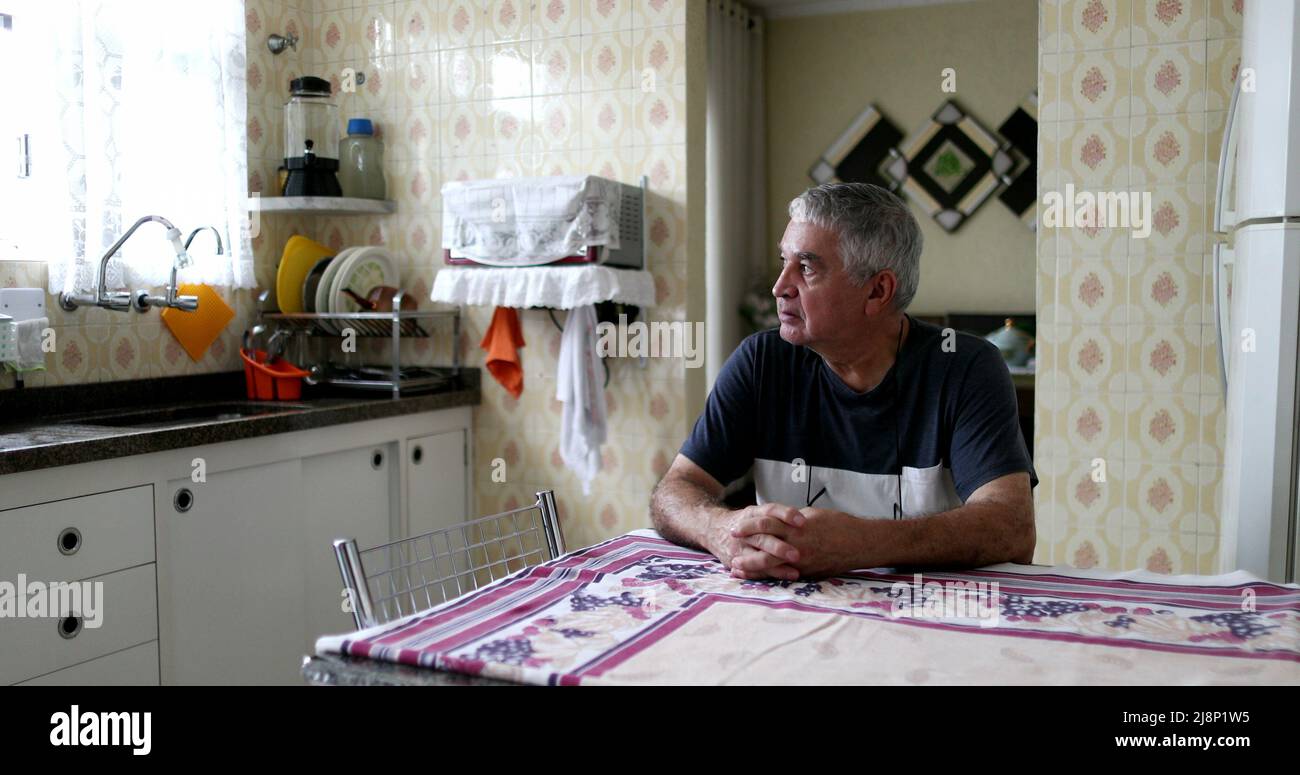 Thoughtful older man sitting at kitchen table. Pensive middle aged ...