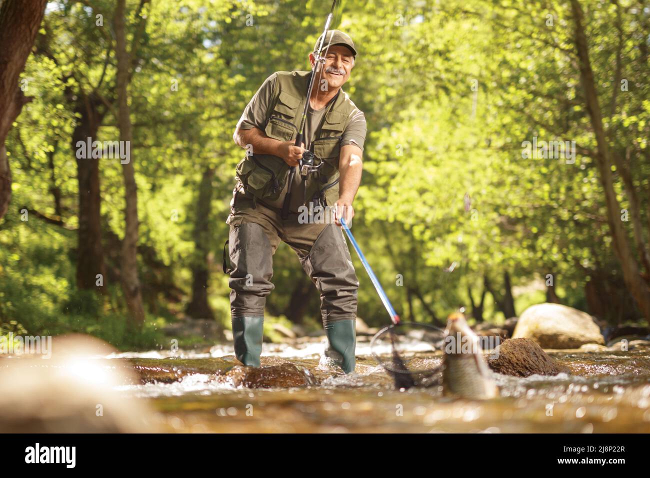 Fisherman catching a big carp fish in a river in the woods Stock Photo ...