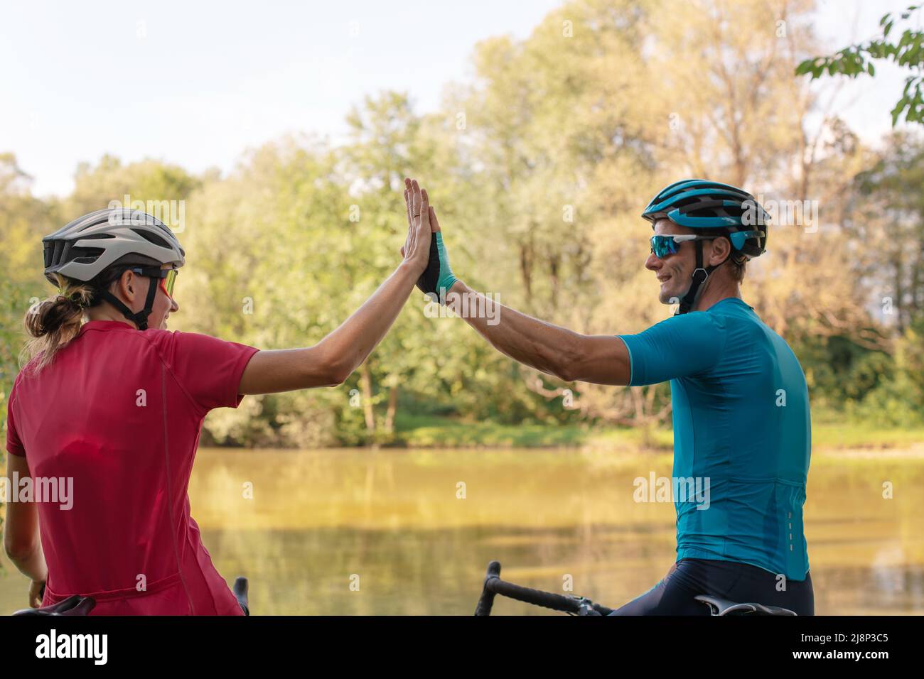 Woman and man, professional road racing cyclists high five each other ...
