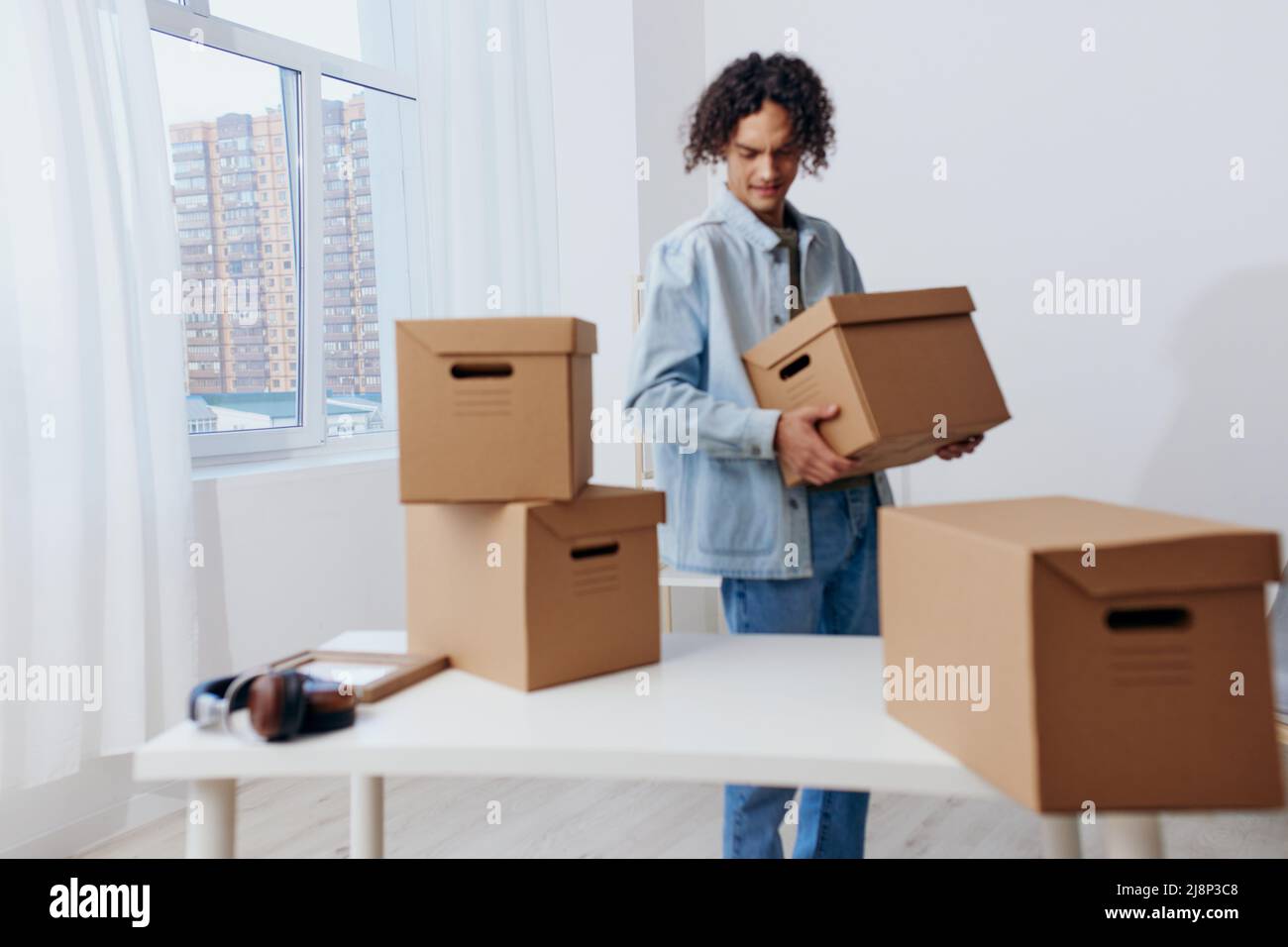 handsome guy unpacking things from boxes in the room interior Stock ...