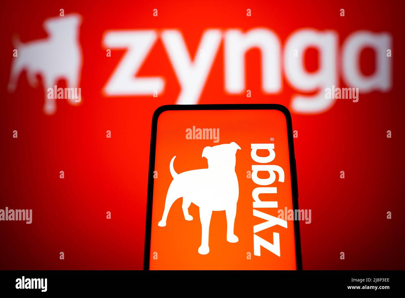 In this photo illustration the Zynga logo seen displayed on a smartphone and in the background ...