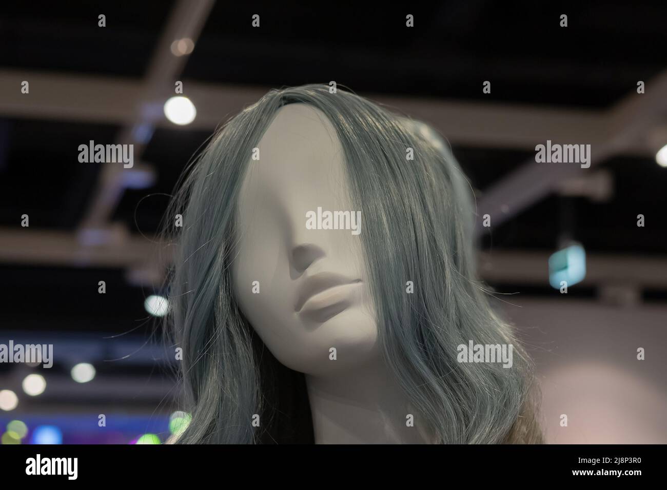 The head of white female mannequin with gray hair against a dark ...