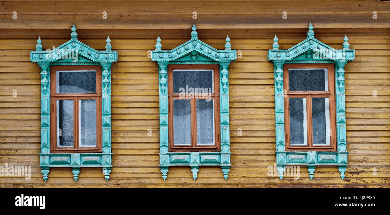 Three old windows with carved wooden architraves on shabby board wall ...