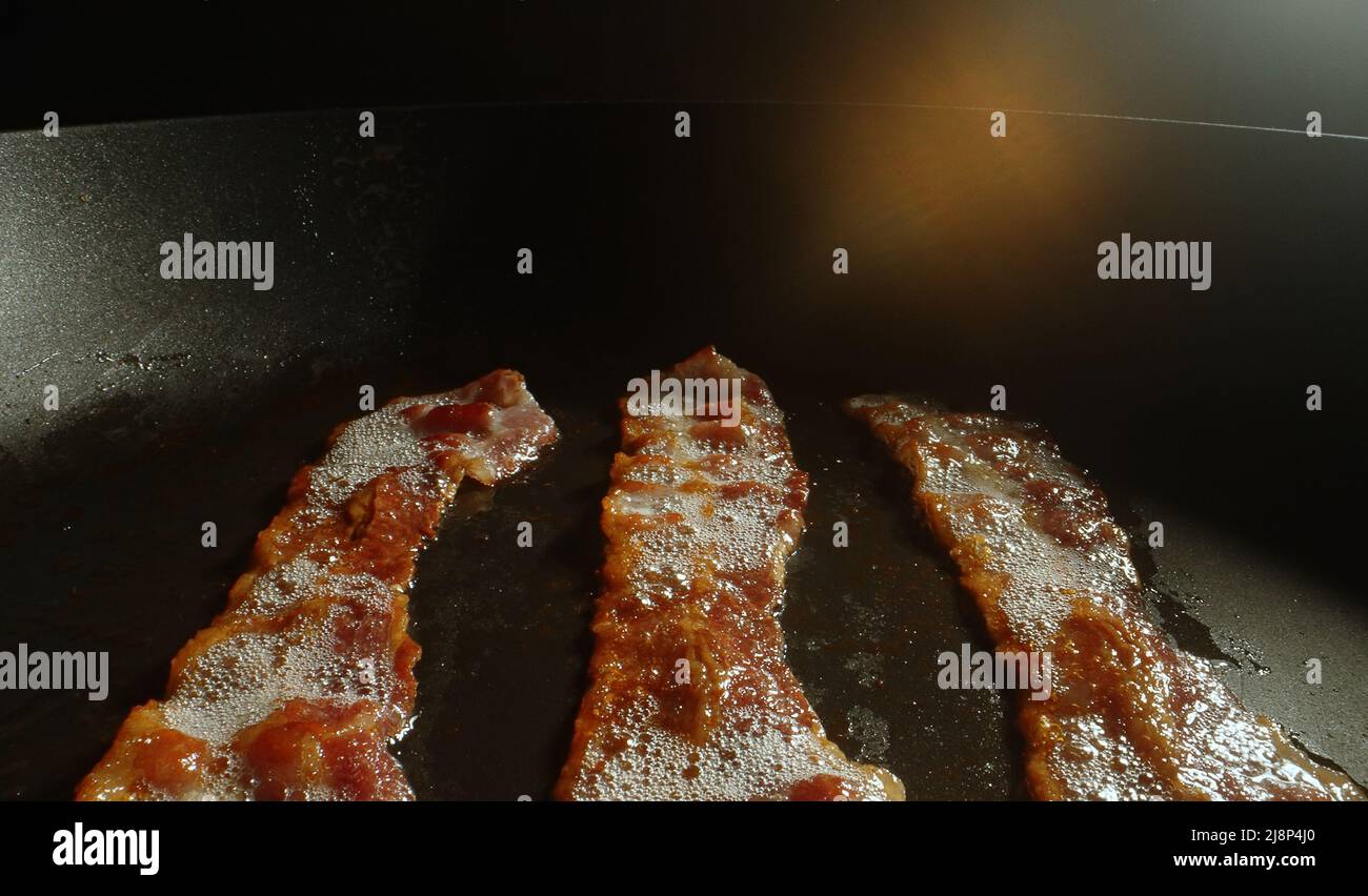 Close-up view of bacon slices in frying pan Stock Photo - Alamy