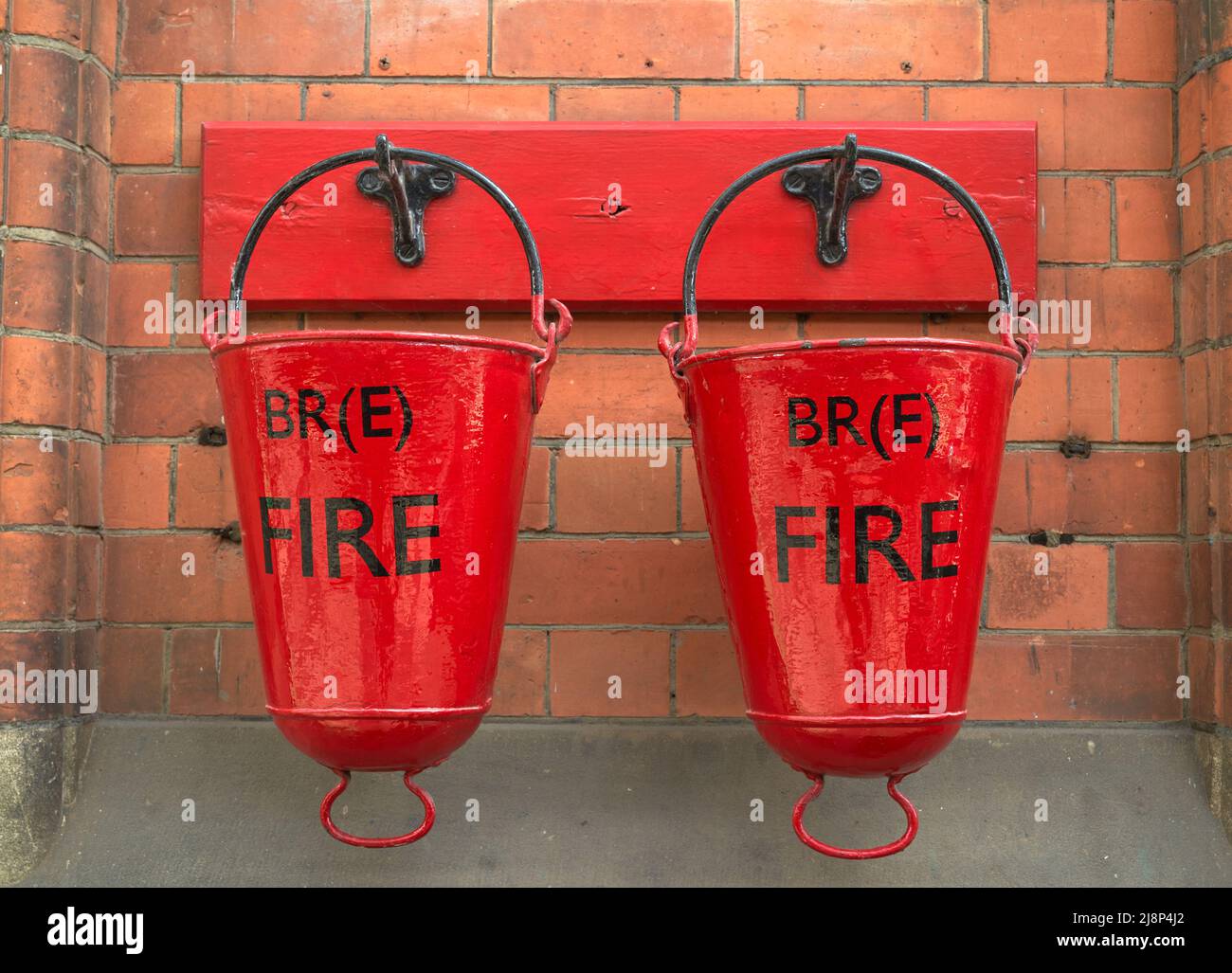 Two old fashioned red fire buckets hanging from a brick wall Stock ...