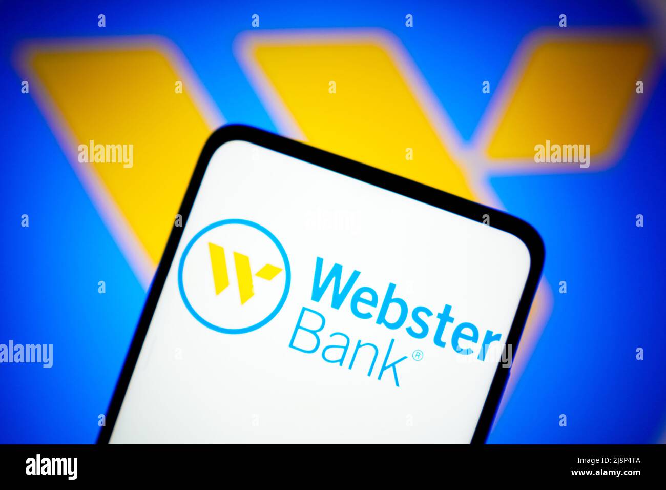 In this photo illustration the Webster Bank logo seen displayed on a smartphone and in the ...