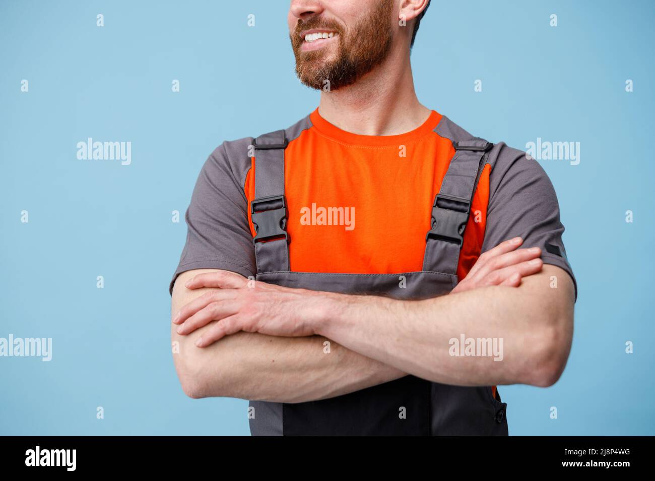 Unrecognizable smiling worker man in uniform with crossed hands looking ...
