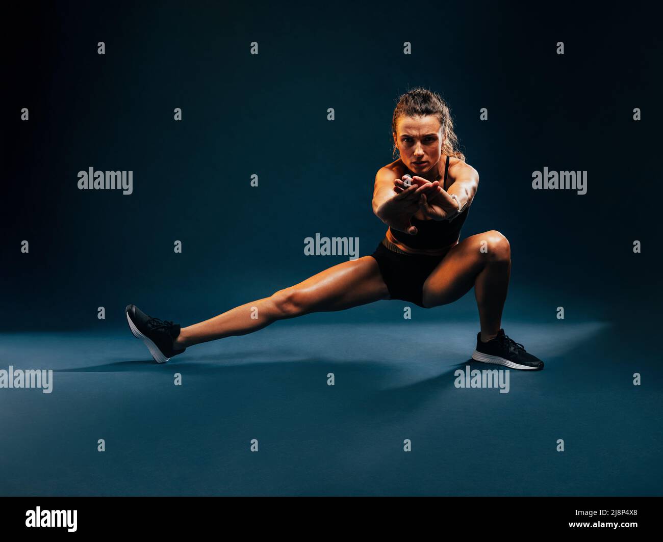 Strong woman doing warming up exercises. Muscular female stretching and ...