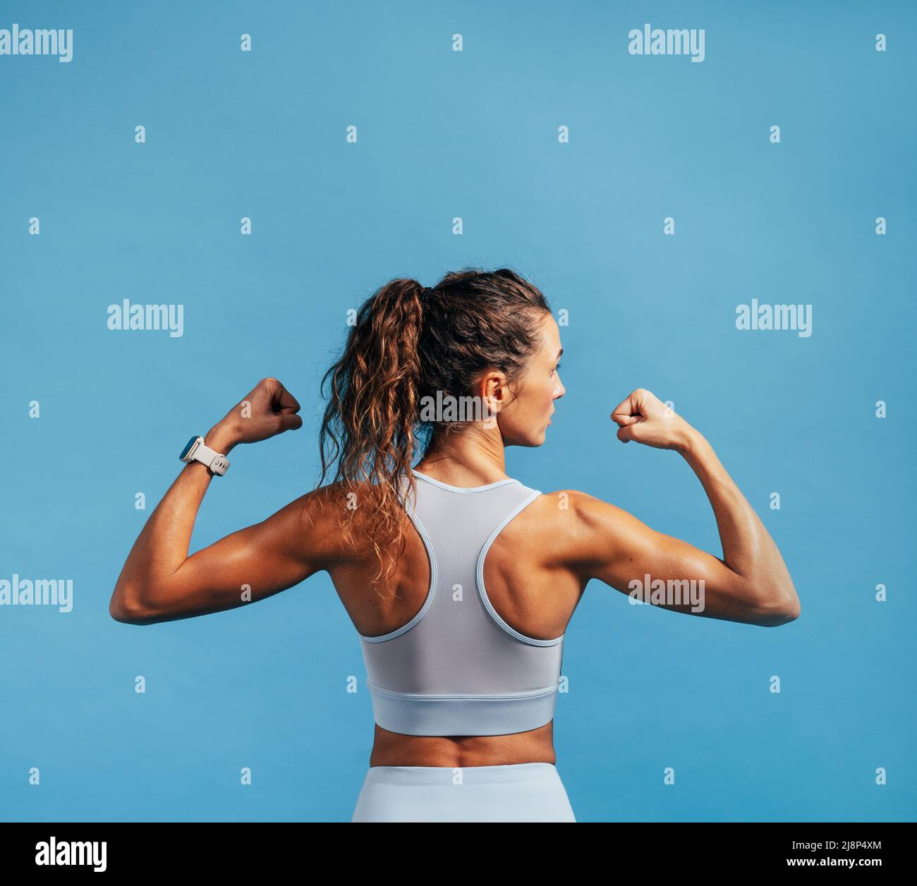 Strong woman in fitness wear showing her biceps. Young healthy female ...