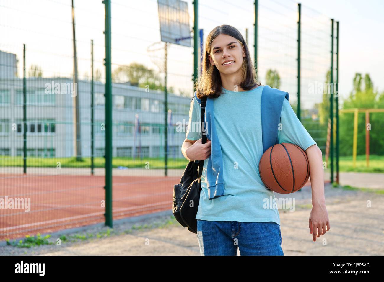 Portrait of student guy with backpack ball, near outdoor basketball ...