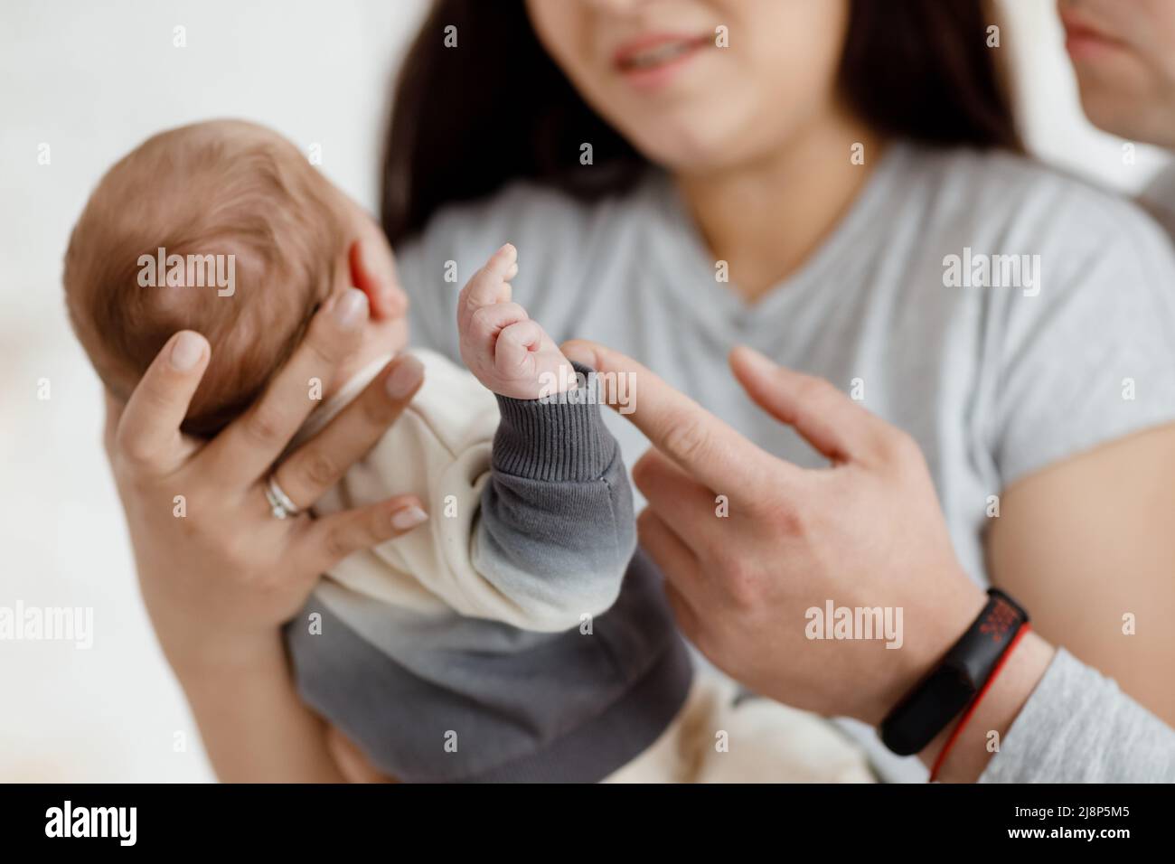 Young parents holding tiny hand of baby. Close up of mom, dad and baby ...