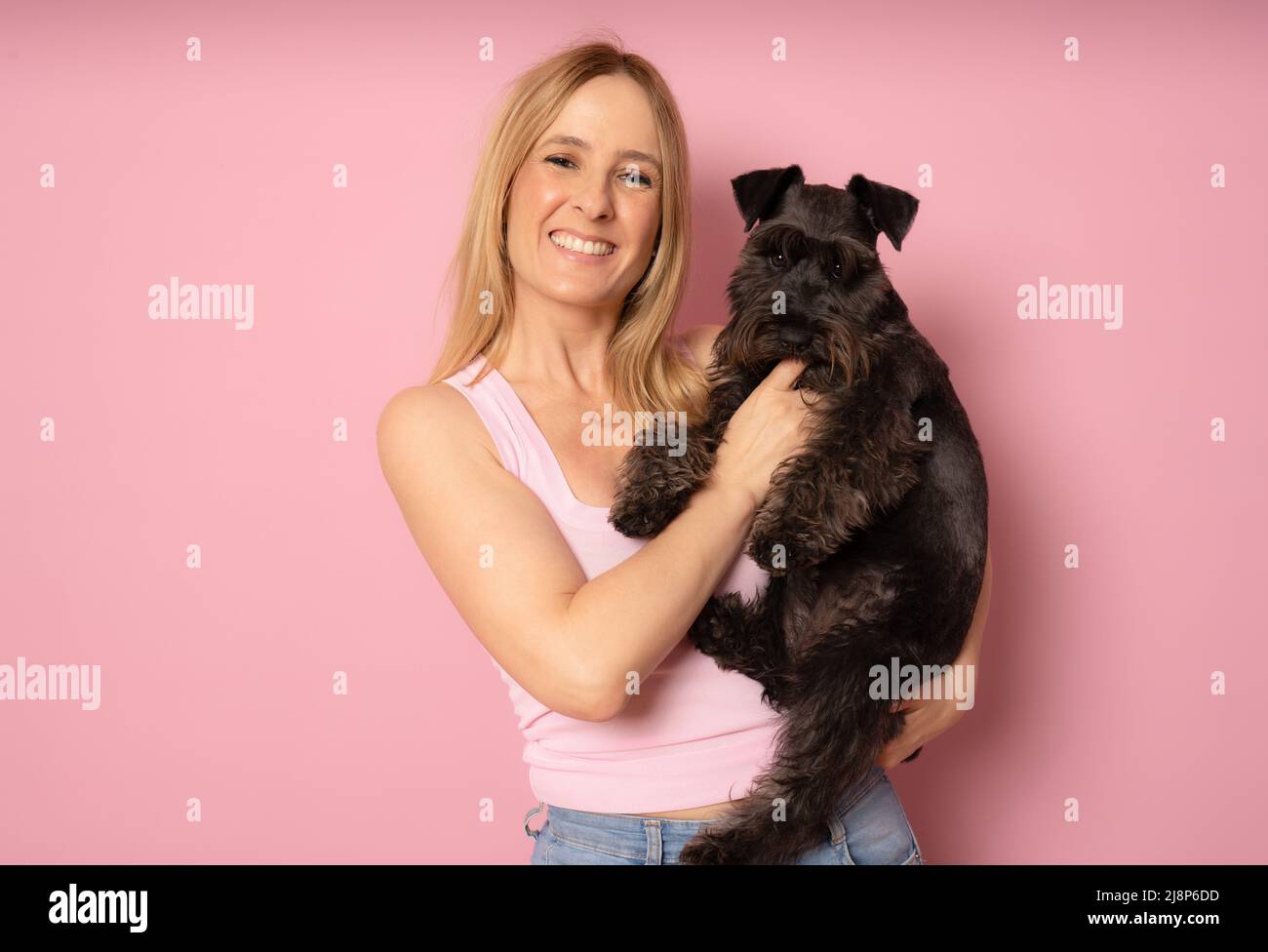 Cute young woman hugs her puppy schnauzer dog. Love between owner and ...