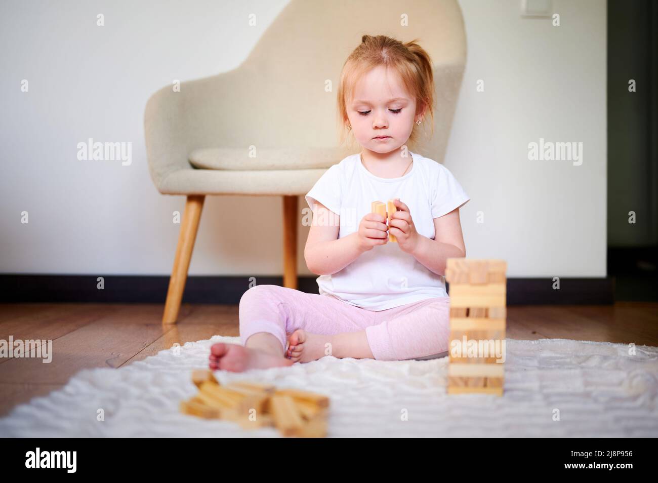 Little cute preschool girl playing jenga on the floor at home and ...