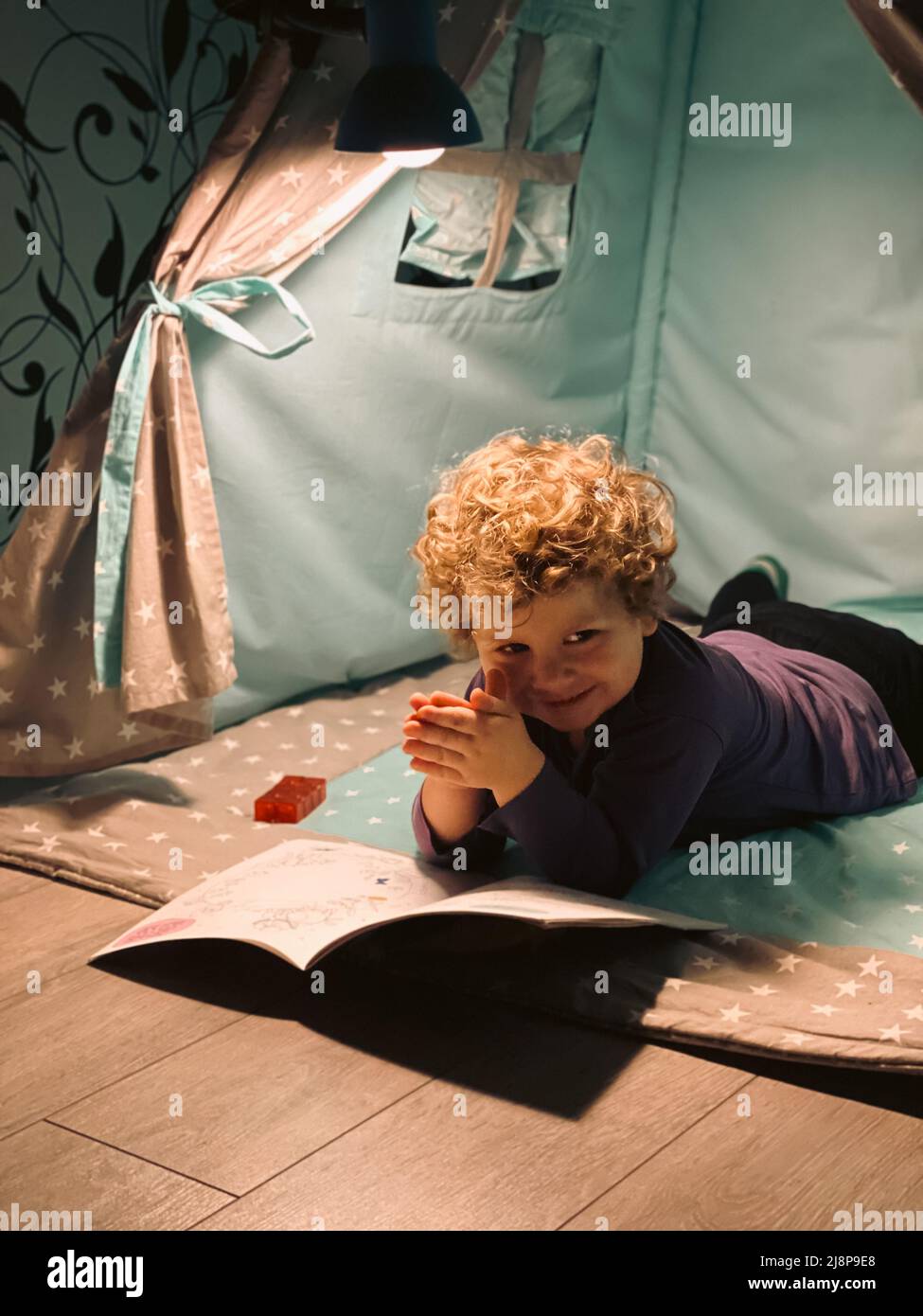 curly-haired boy examines a book in a wigwam Stock Photo - Alamy