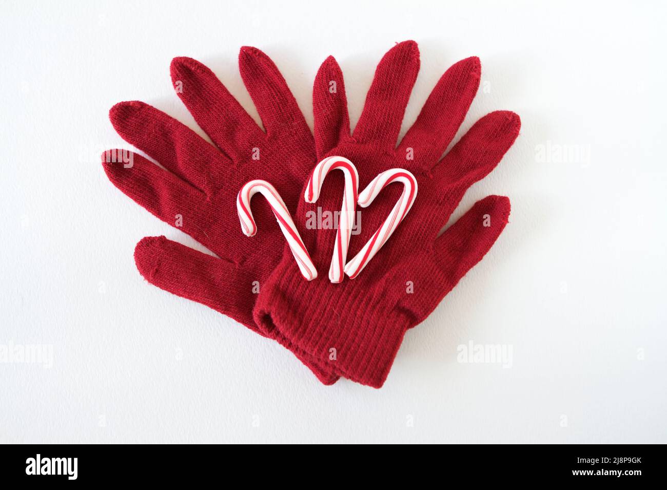 Red winter mittens and three candy canes on white background, image ...