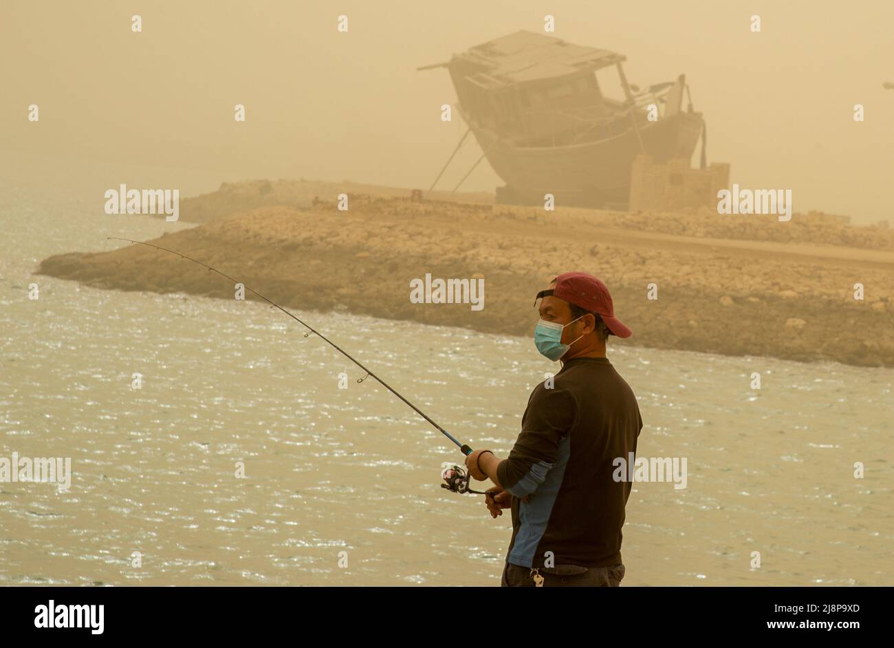 Doha, Qatar. 17th May, 2022. A man fishes during a sandstorm in Doha ...