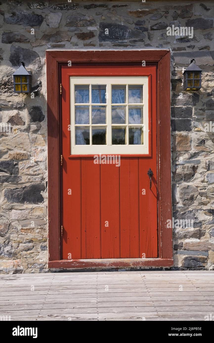 Red wood plank entrance door with glass pane window on facade of old ...