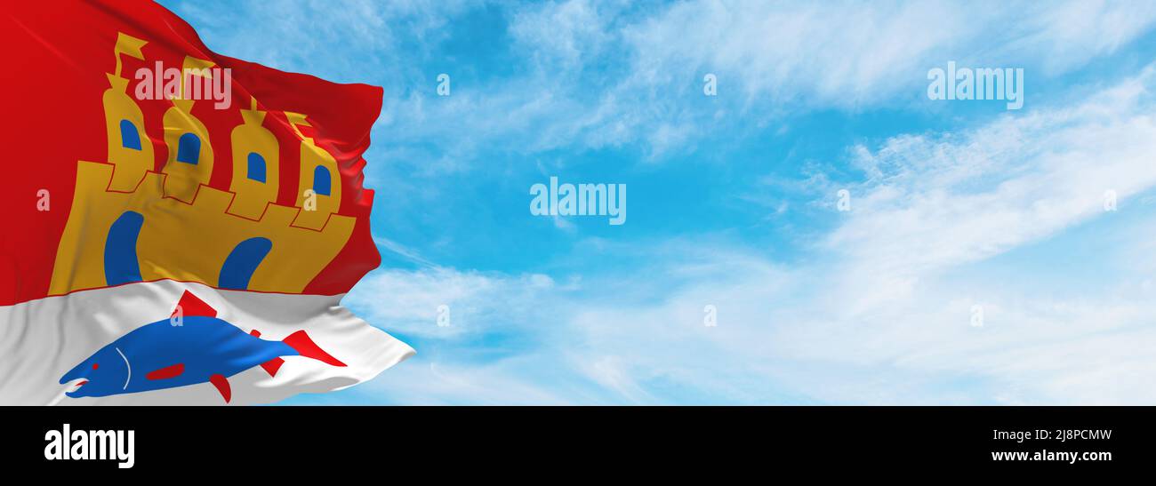 official flag of Oulu , Finland at cloudy sky background on sunset ...