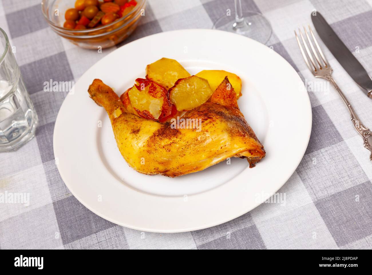 Baked chicken leg served on plate with side dish of fried potatoes ...