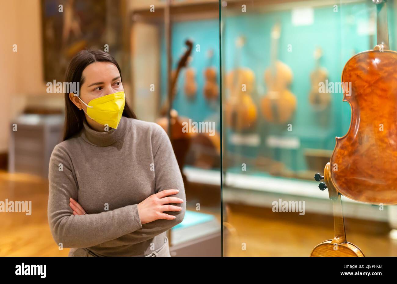 Brunette in protective mask visiting exhibition of medieval musical ...