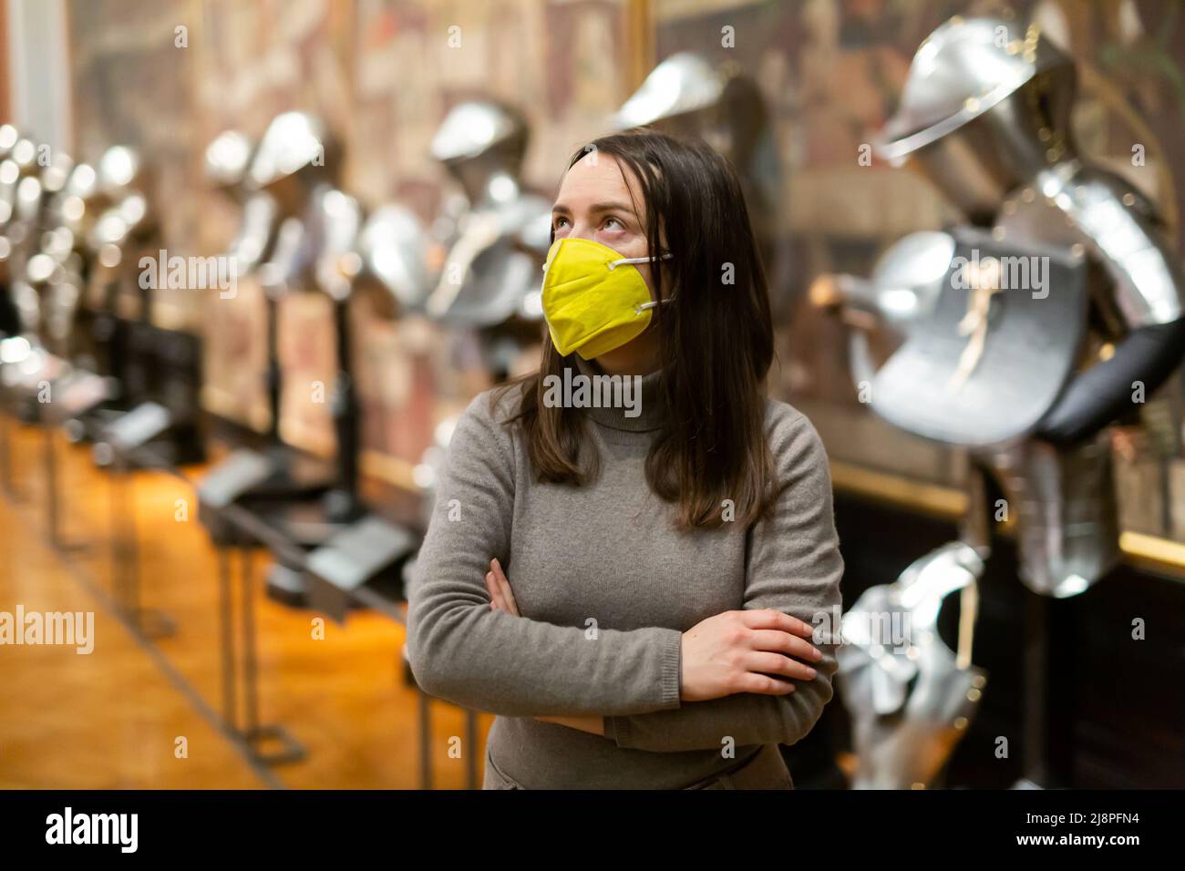 Interested brunette in mask visiting exhibition of historical museum ...