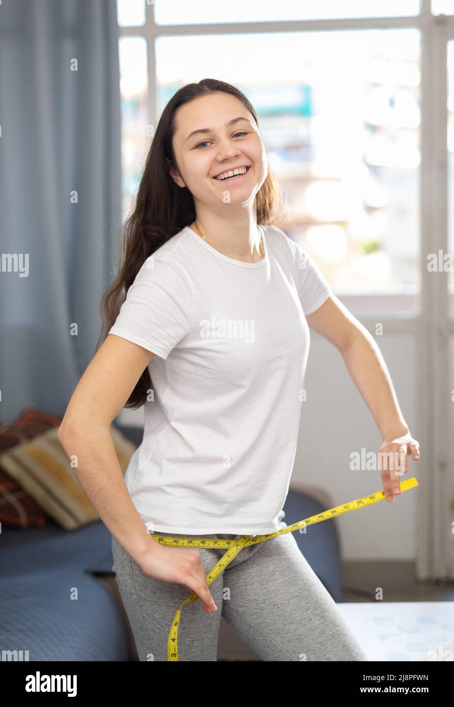 Positive woman measuring thigh with measuring tape Stock Photo - Alamy