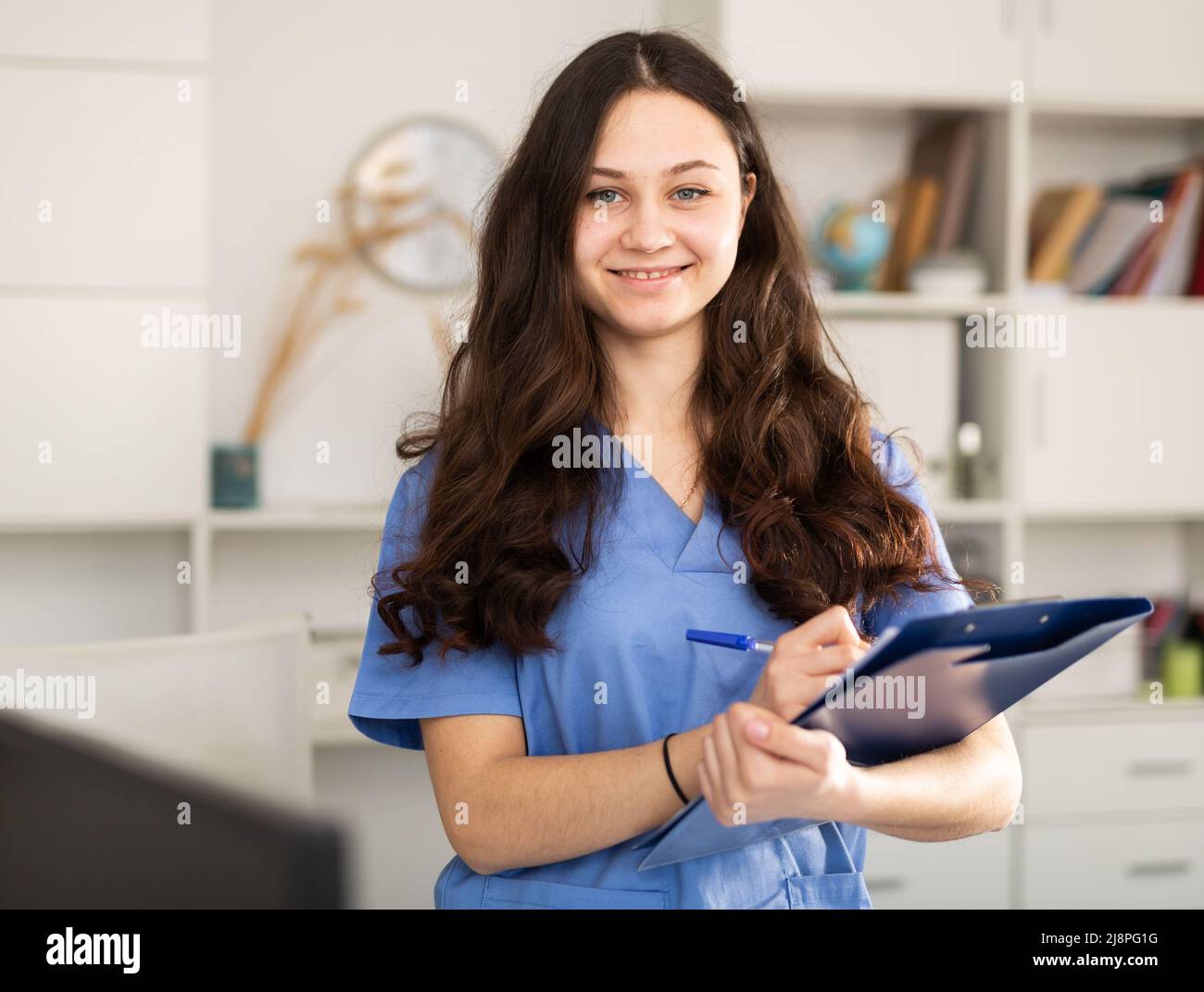 Positive woman doctor in formal wear standing with folder Stock Photo ...