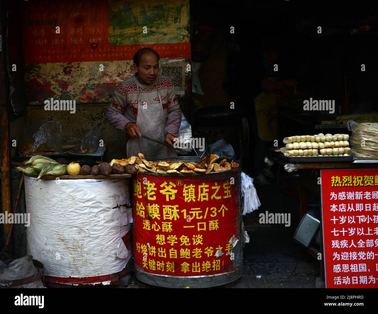 A Chinese man baking pastries in a barrel tandoor oven in Nanjing ...