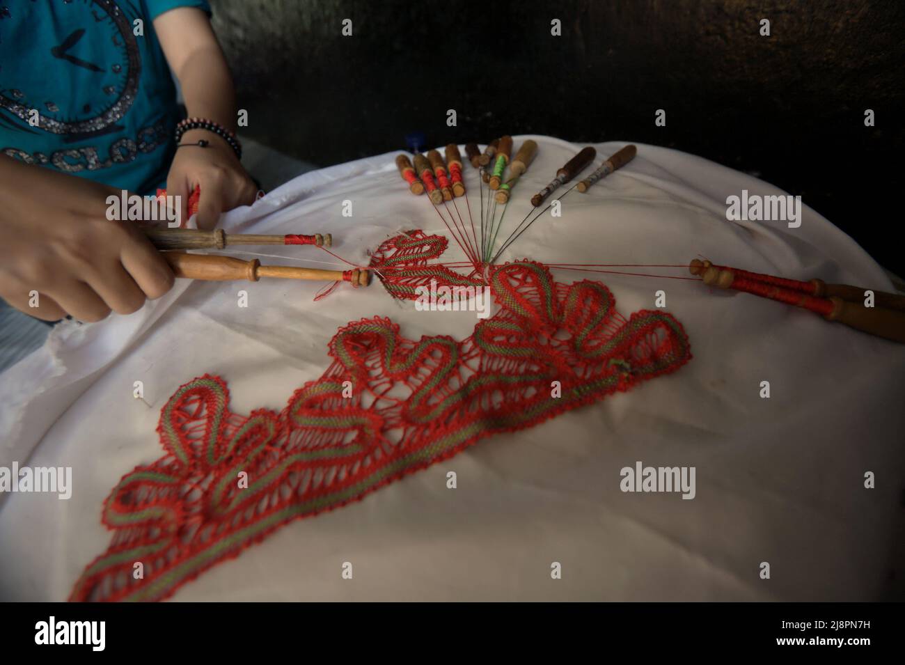 A woman knitting decorative patterns on textile using traditional tool ...