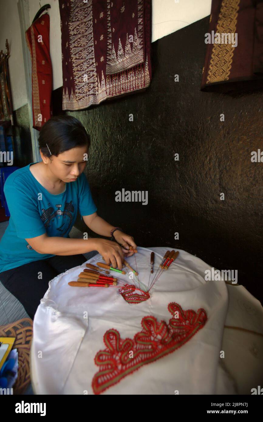 A woman knitting decorative patterns on textile using traditional tool ...