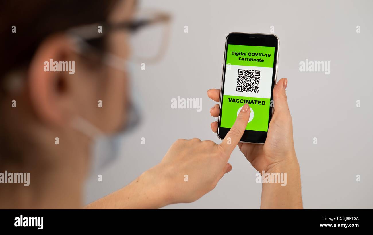 The doctor holds a smartphone with a QR code about the vaccination ...