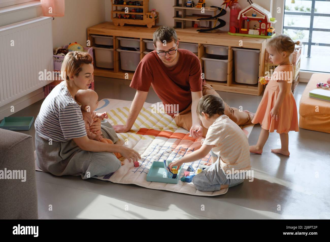 Big family in sunny play room. Parents playing with kids and toys ...