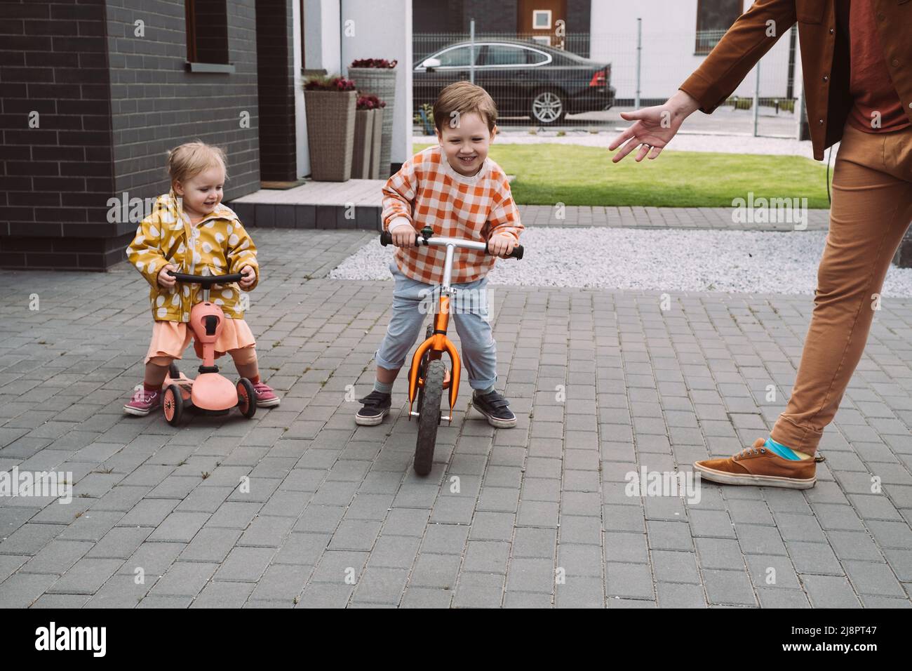 Children playing racing on bike and scooter in the home yard. Sister ...