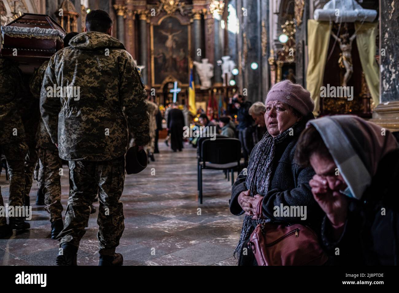Two women cry while soldiers enter carrying a coffin of a dead soldier ...