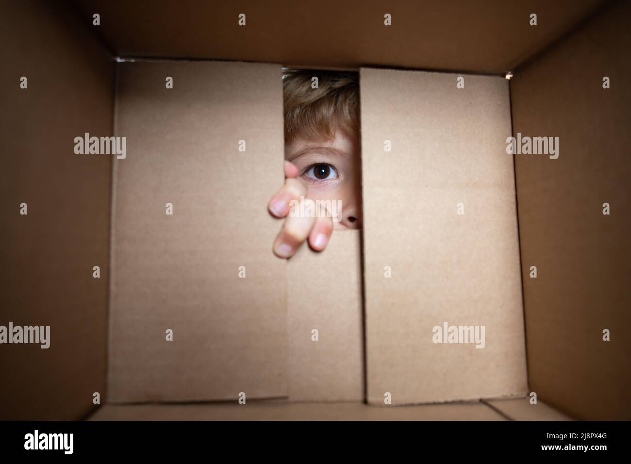 Excited child boy looking into the box, shipping cardboard box. Close ...