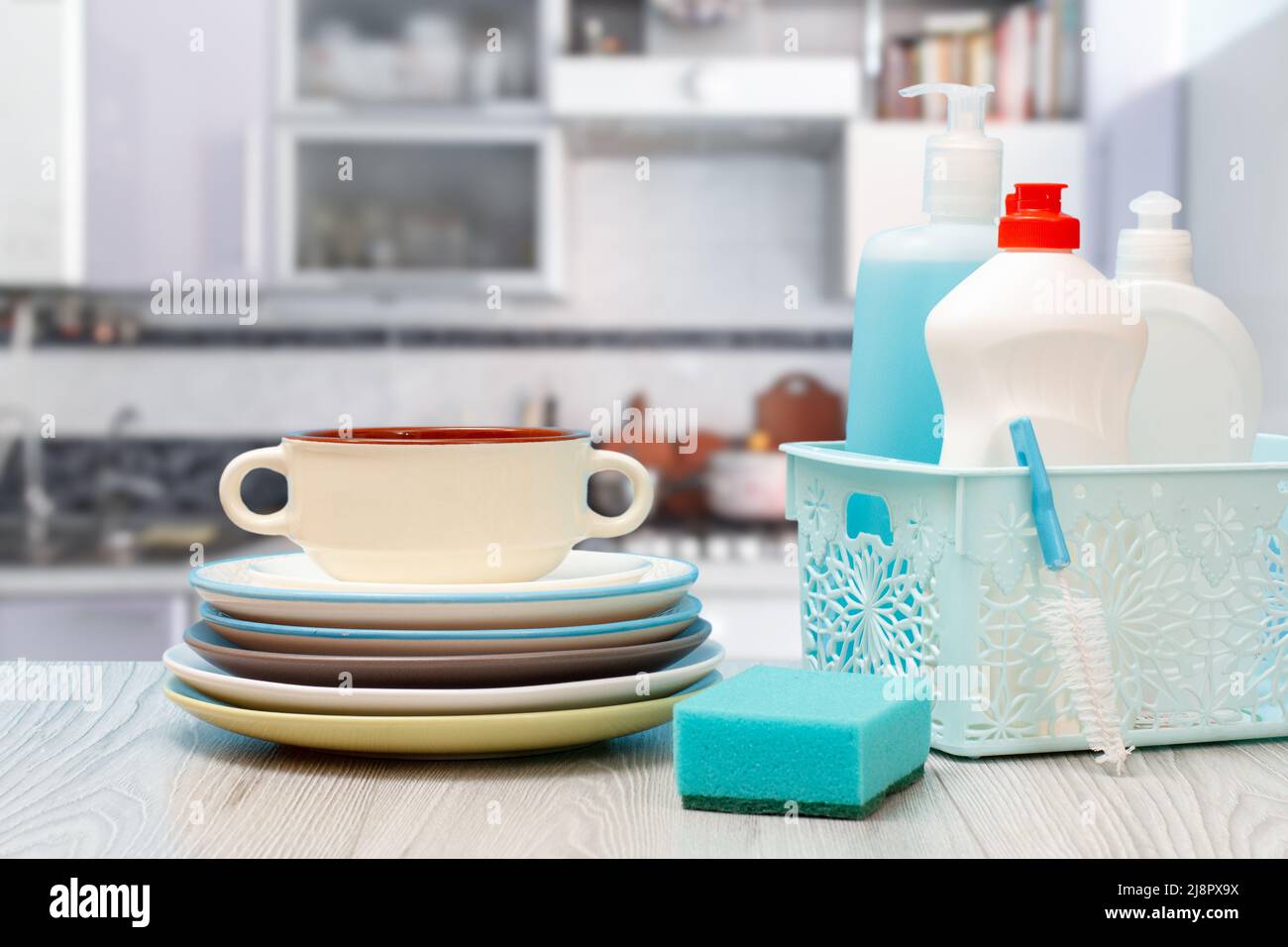 Plastic bottles of dishwashing liquid, glass and tile cleaner in basket ...