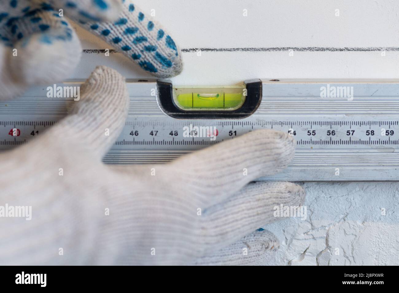 Worker hands check the evenness of the wall with a special tool for ...