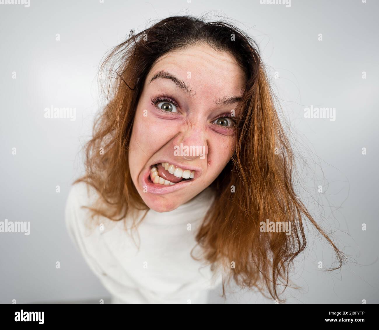 Close-up portrait of insane woman in straitjacket on white background ...