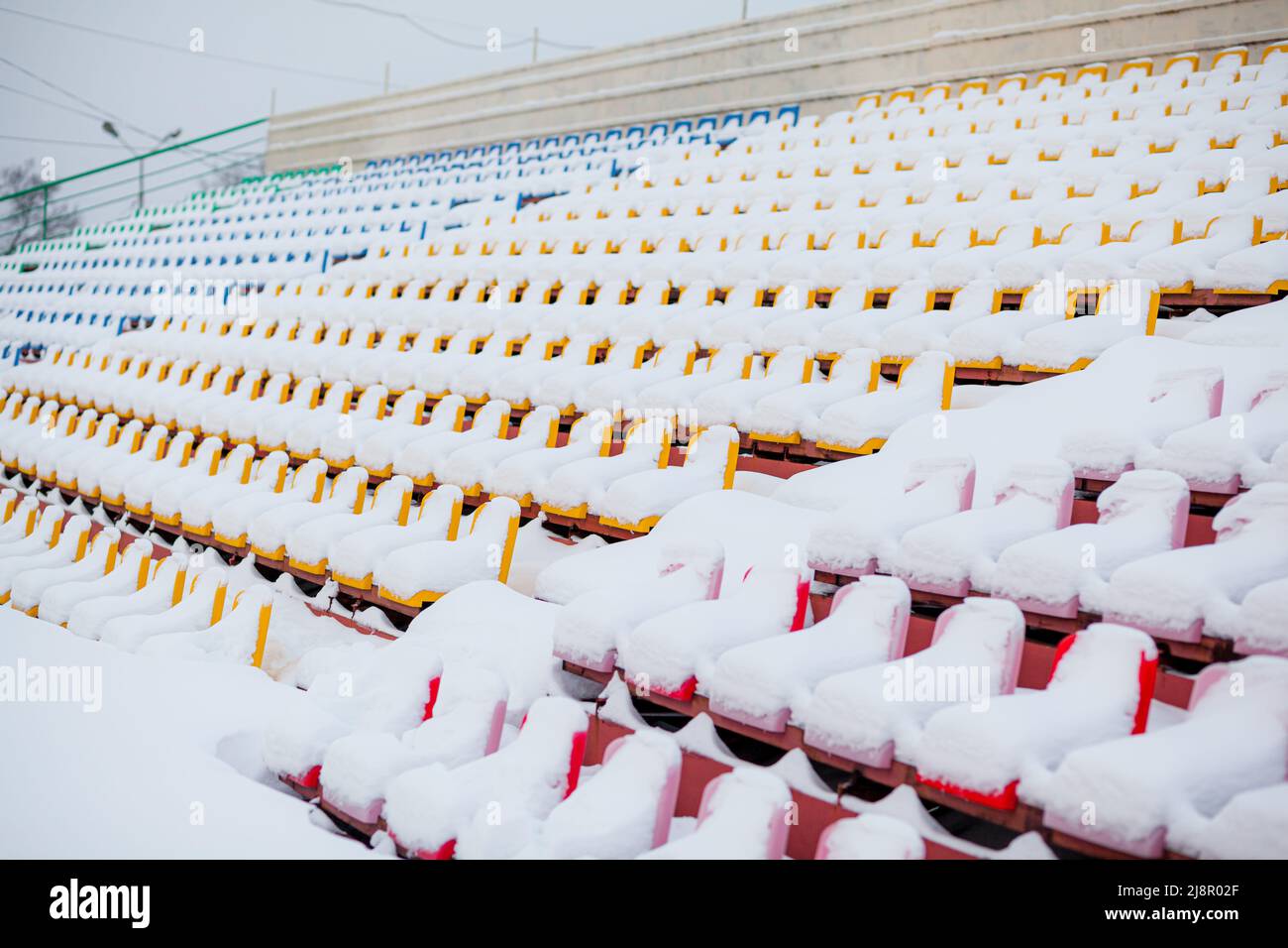 Empty outdoor football soccer stadium seats covered with snow in winter ...