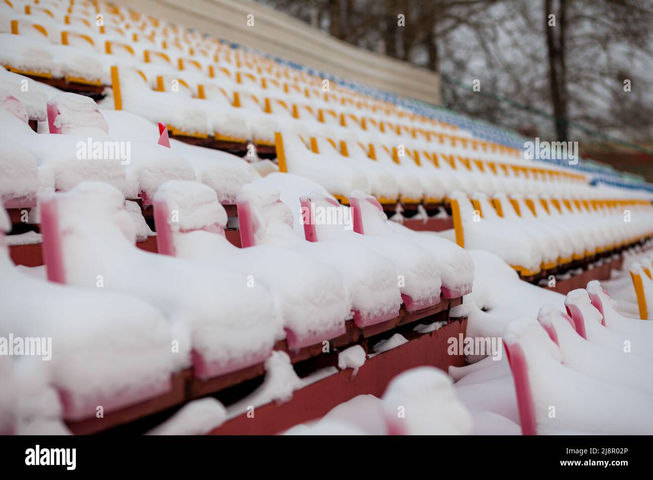 Empty outdoor football soccer stadium seats covered with snow in winter ...