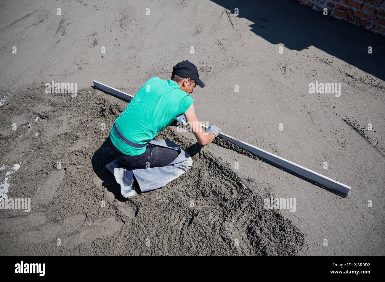 Top view of male worker placing screed rail on the floor covered with ...