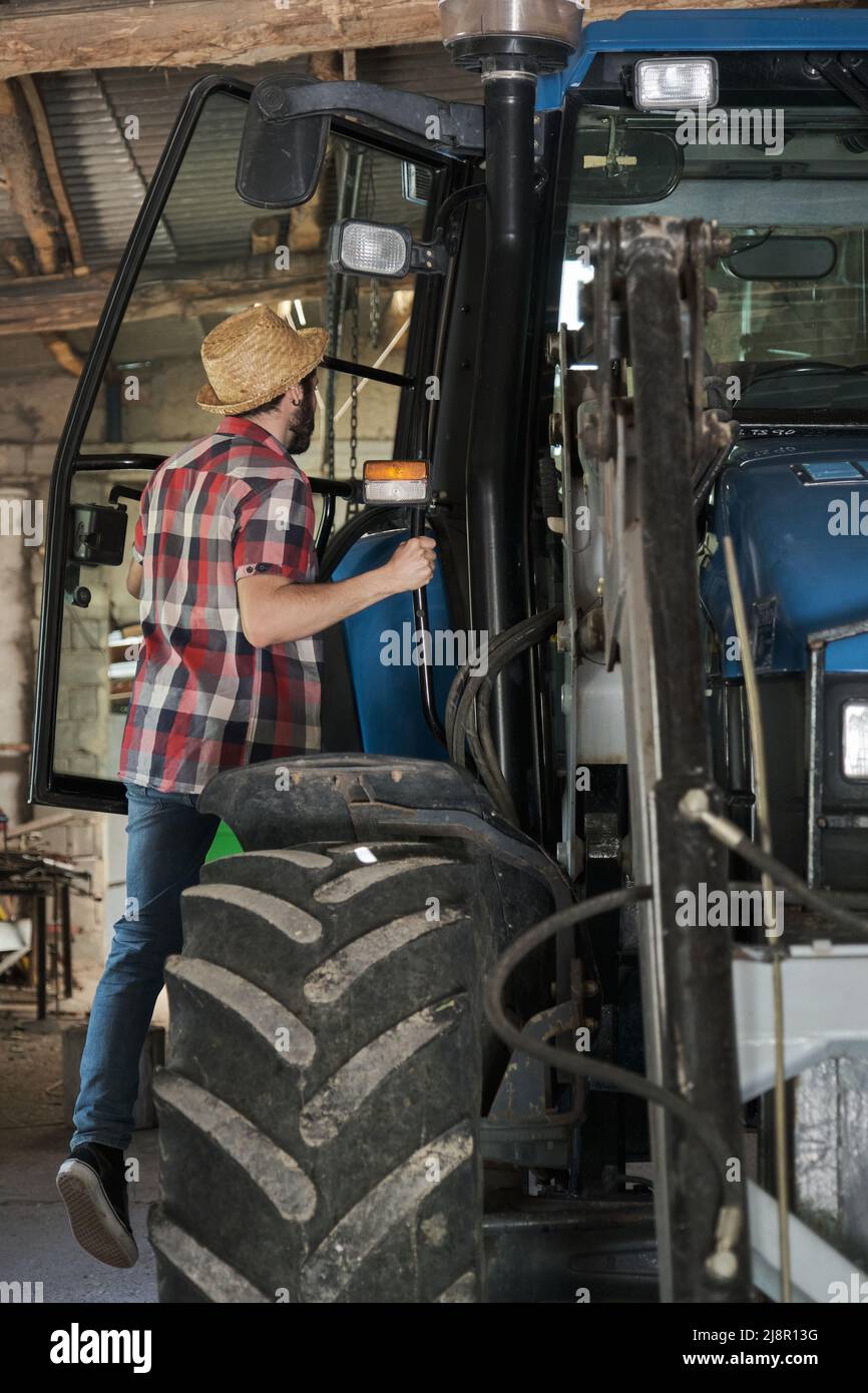 Young farmer climbing in a tractor in a barn Stock Photo - Alamy