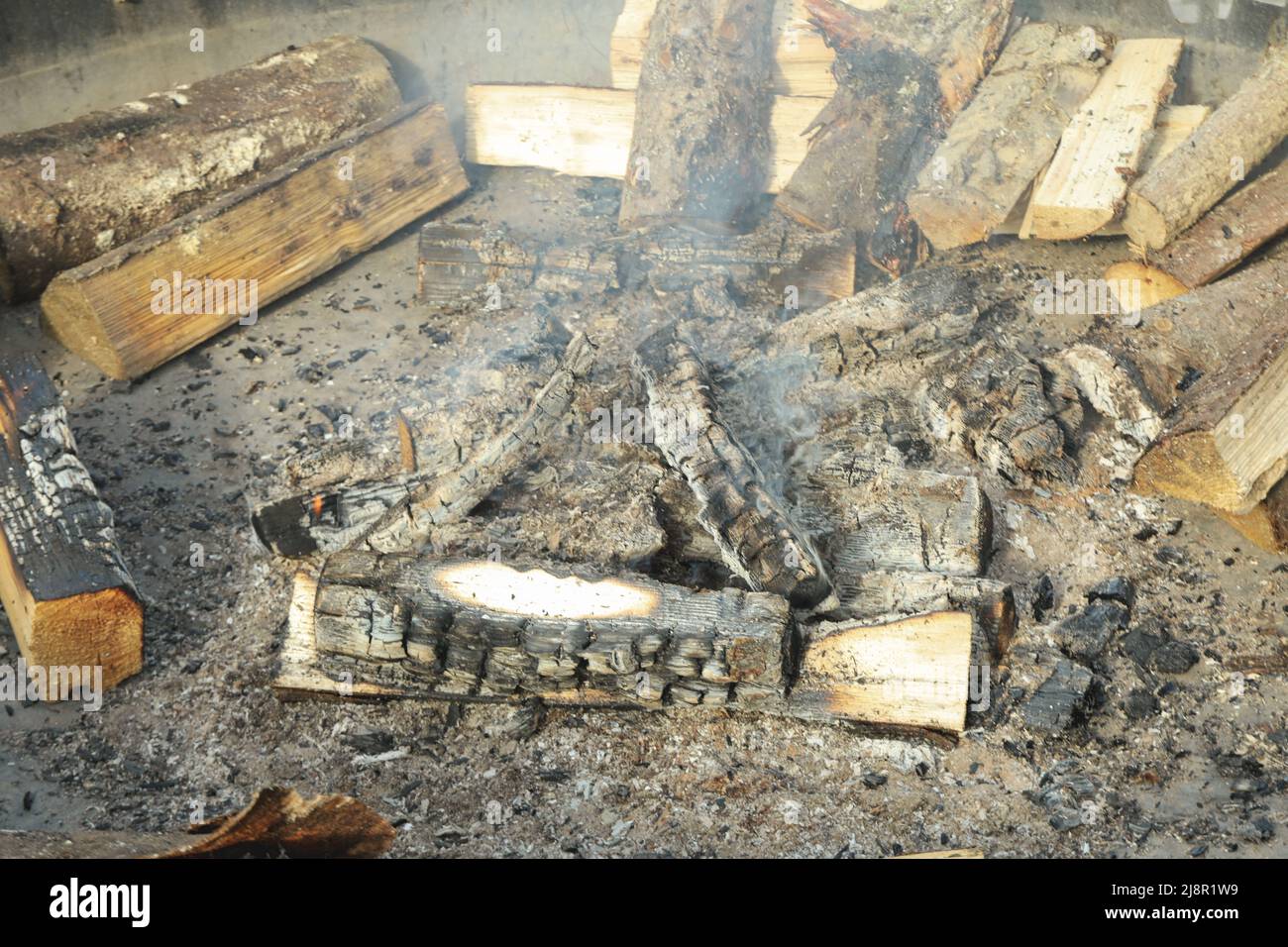 Bonfire with smoldering wood and firewood pieces Stock Photo - Alamy