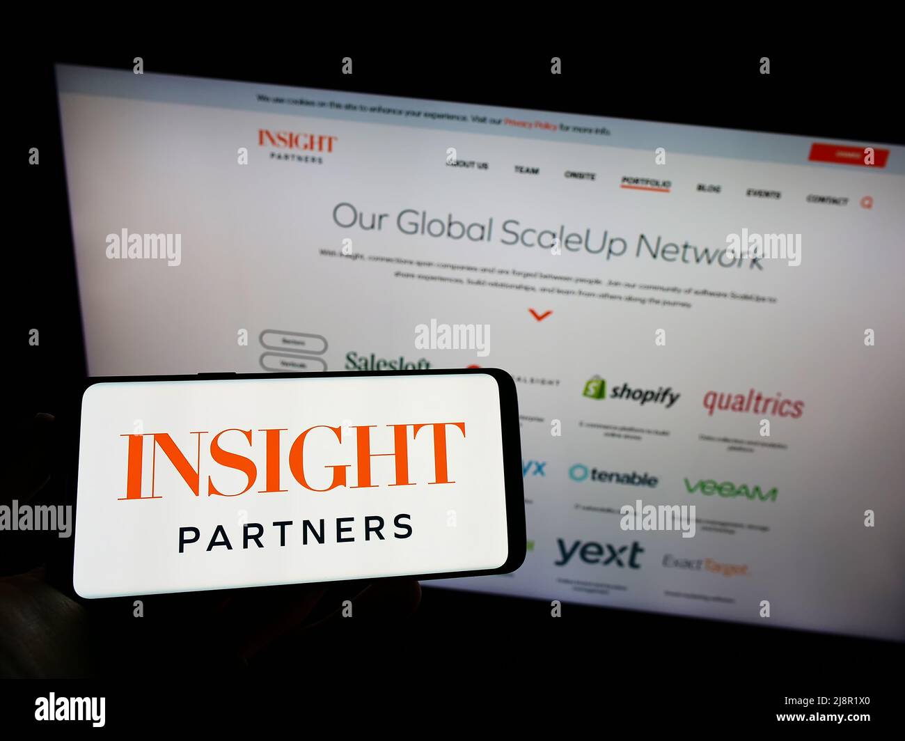 Person holding mobile phone with logo of American investment company ...