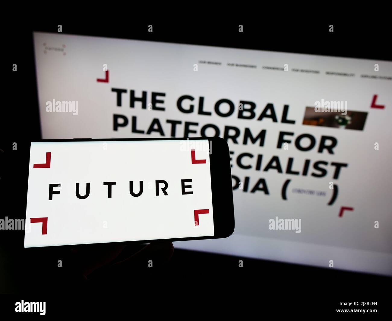 Person holding mobile phone with logo of British media company Future ...
