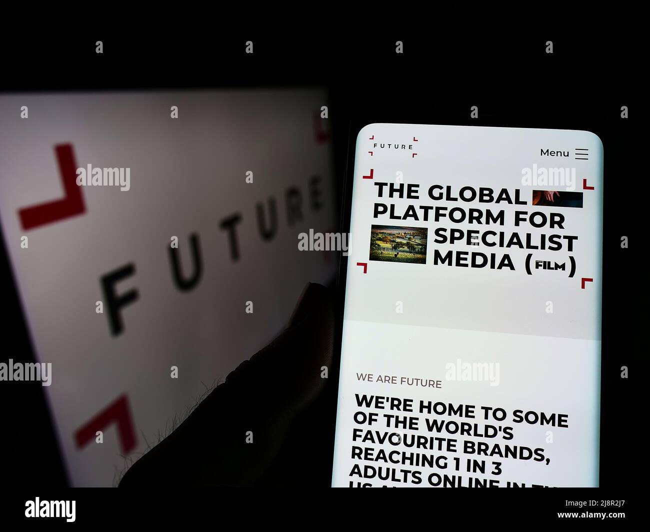 Person holding cellphone with webpage of British media company Future ...